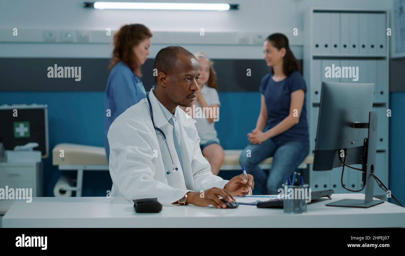 African american physician with stethoscope working on computer in ...