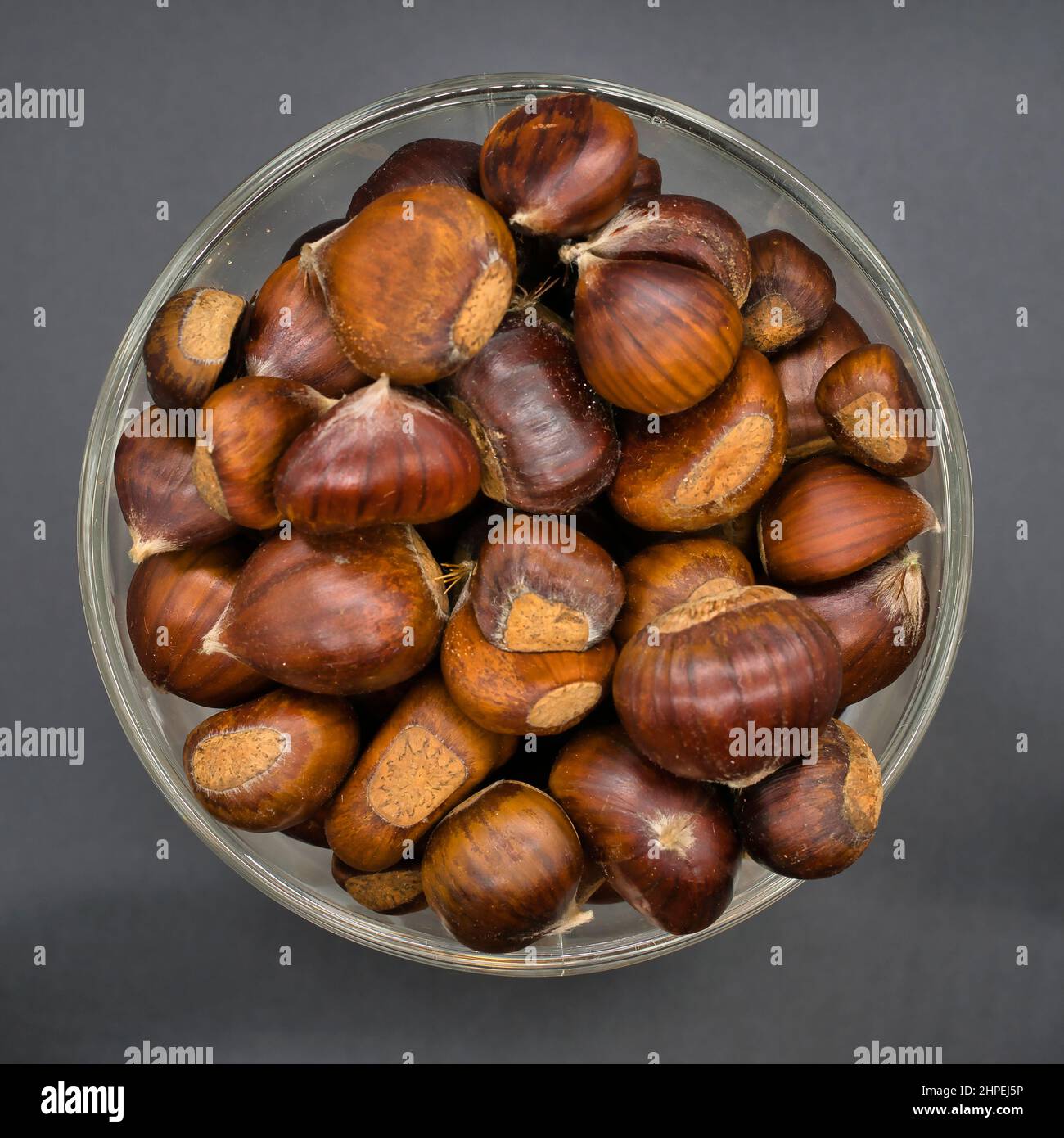 many fresh chestnuts in a glass bowl photographed from above with dark ...