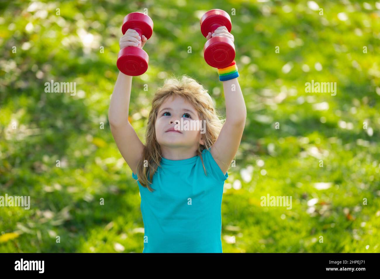 Child boy raising a dumbbell. Cute child training with dumbbells ...