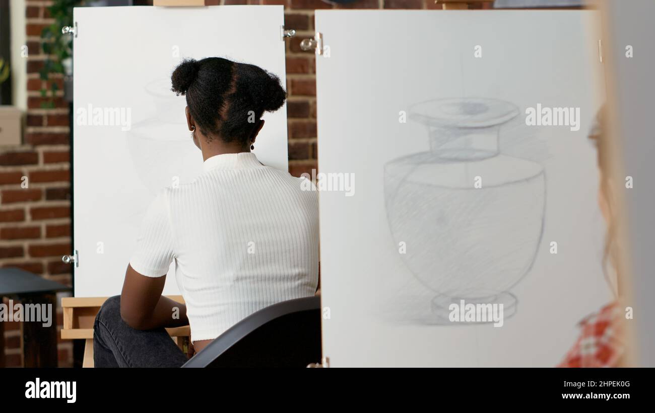 Female student using pencil and canvas to create artwork in art and ...