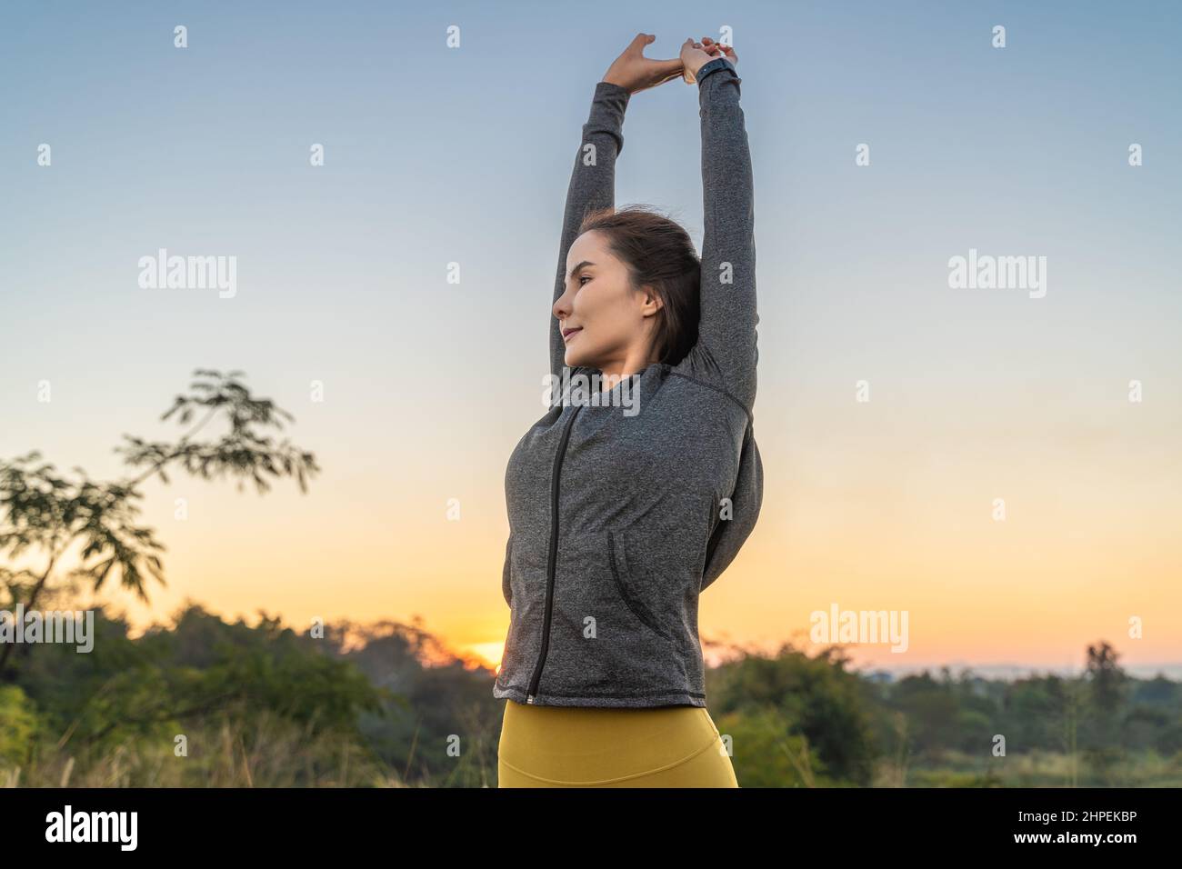 Attractive young woman stretching her arms and legs before her early ...
