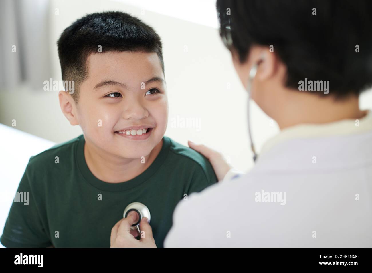 Asian little boy smiling to doctor while she examining his heartbeat ...