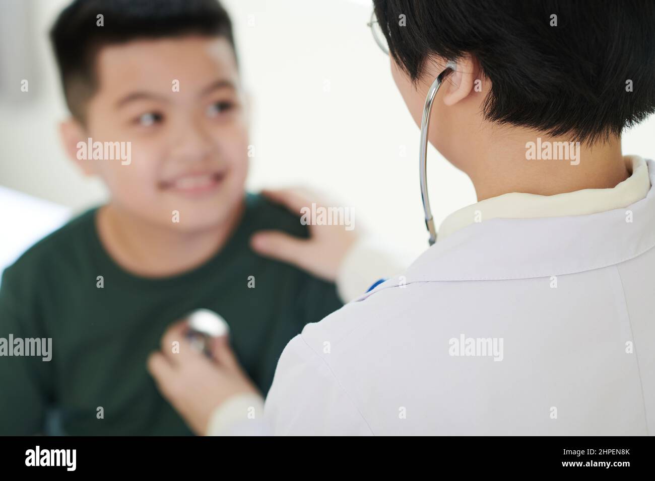 Rear view of female doctor examining the boy with stethoscope during ...