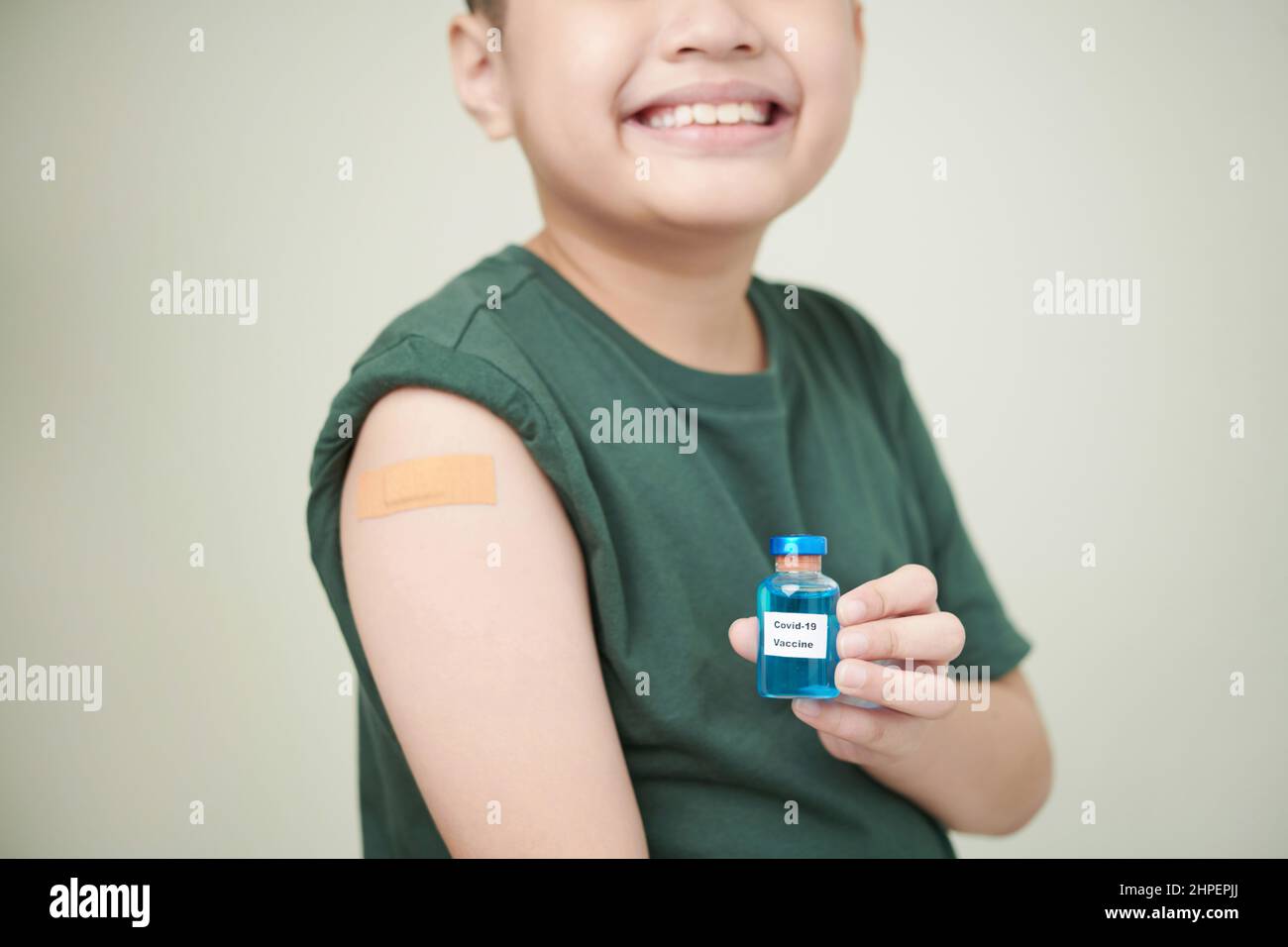 Close-up of little boy with plaster on his arm holding the bottle with ...