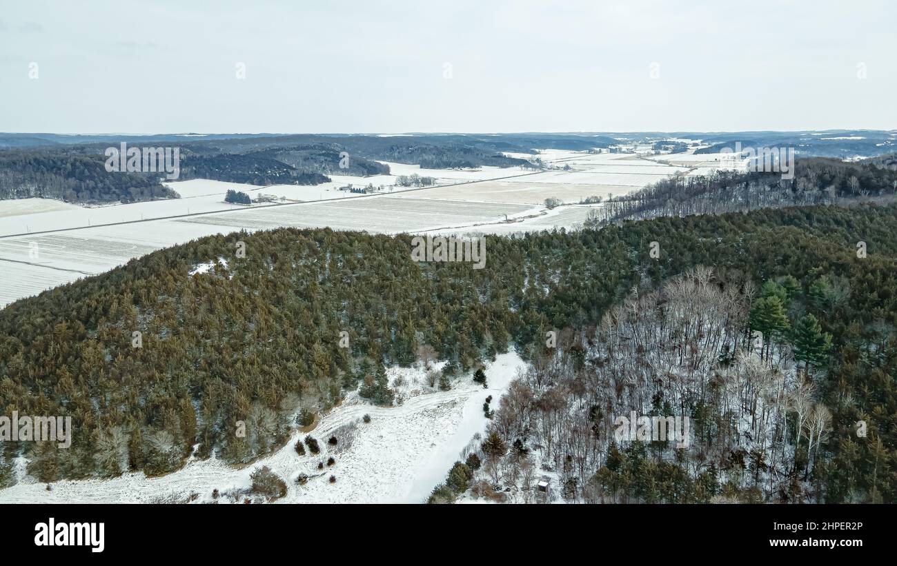 Snow covers the hills and fields with farm fields between the slopes ...