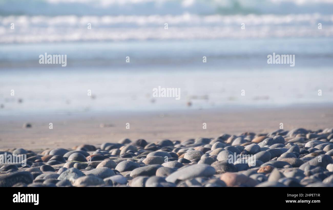 Pebble rocks on sandy beach by ocean sea water waves, round smooth ...