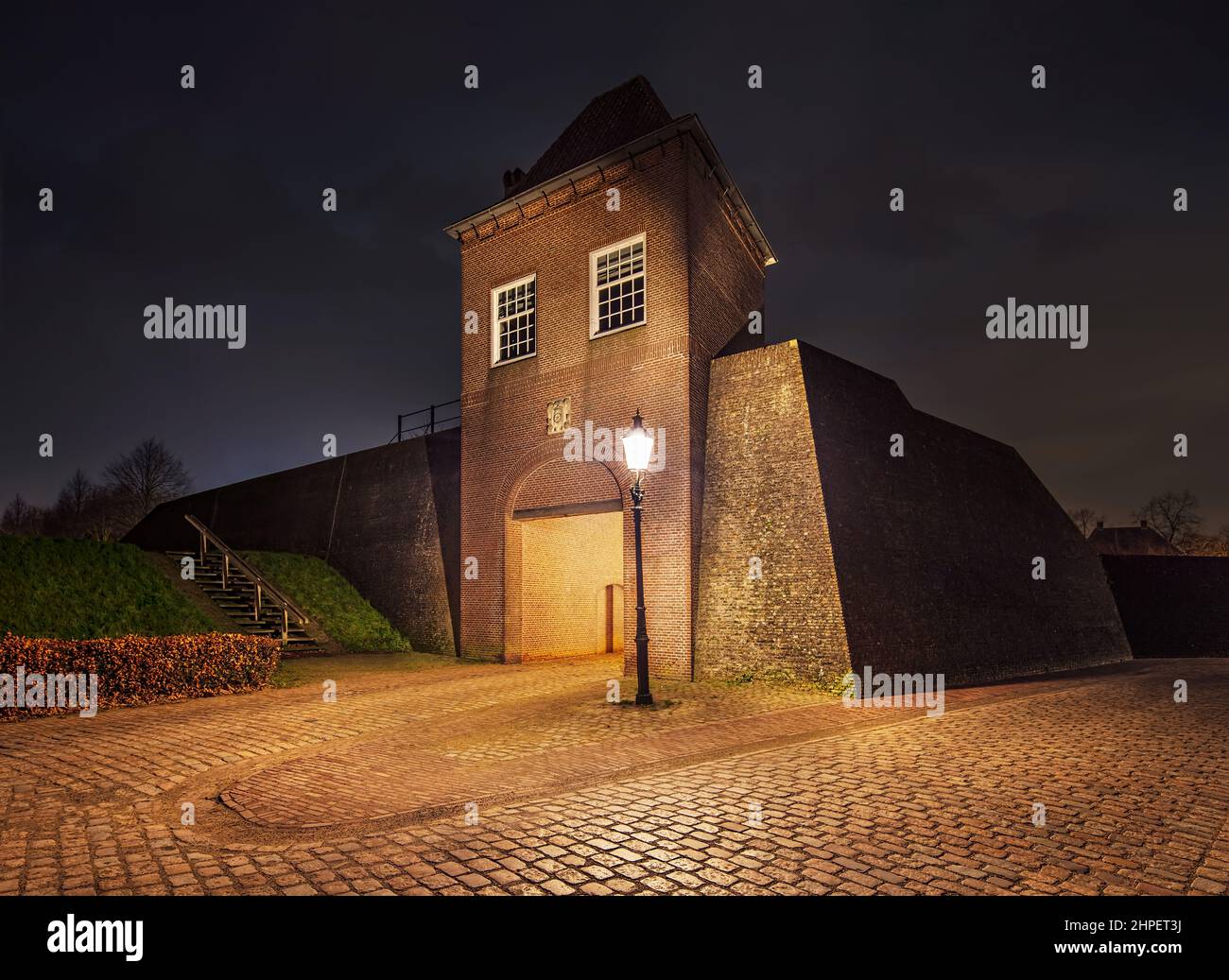 Night scene with illuminated brick gatehouse of historical fortified ...