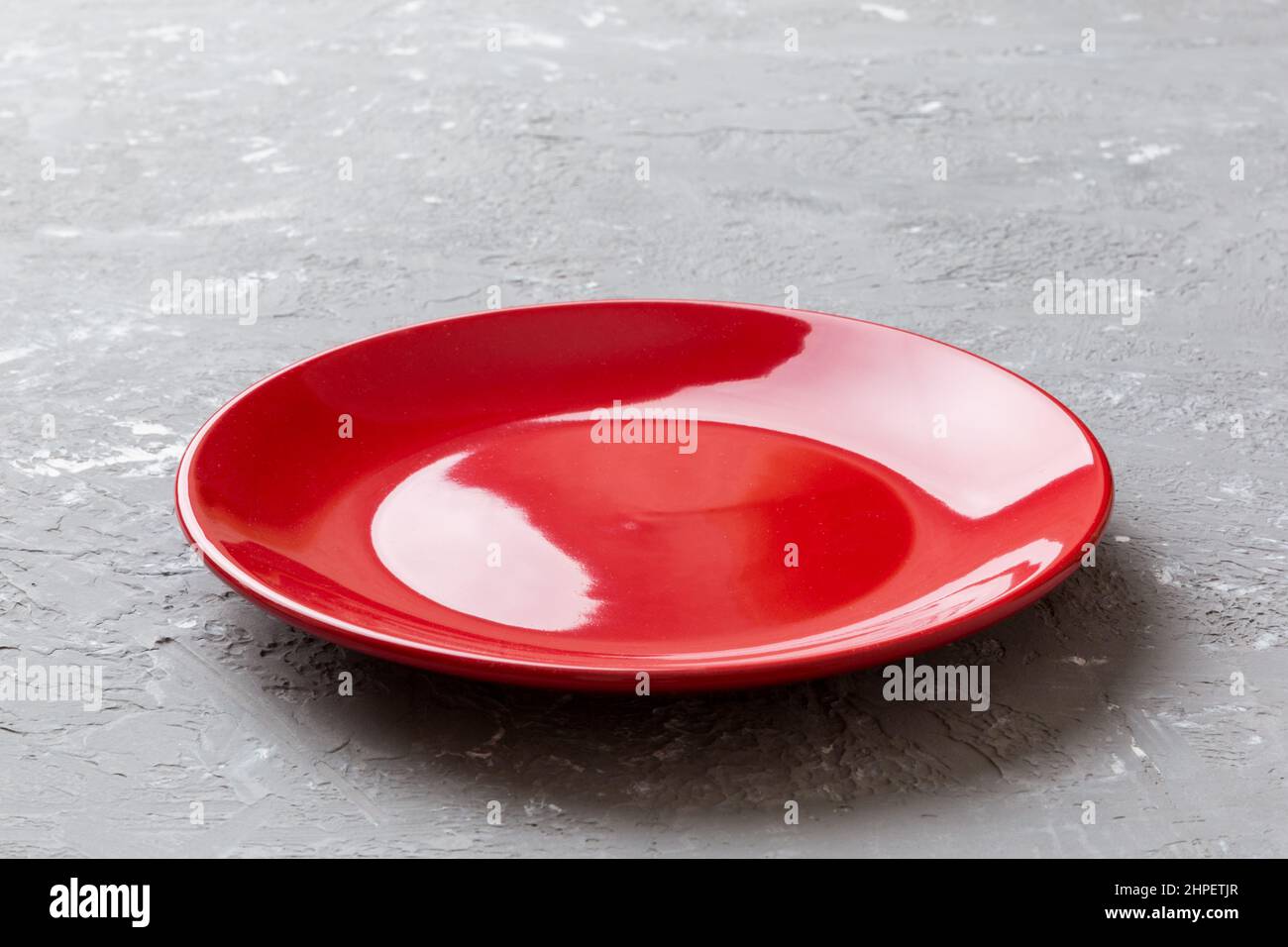 Perspective view of empty red plate on cement background. Empty space ...