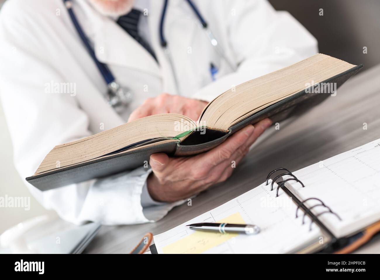 Doctor reading a textbook in medical office Stock Photo - Alamy