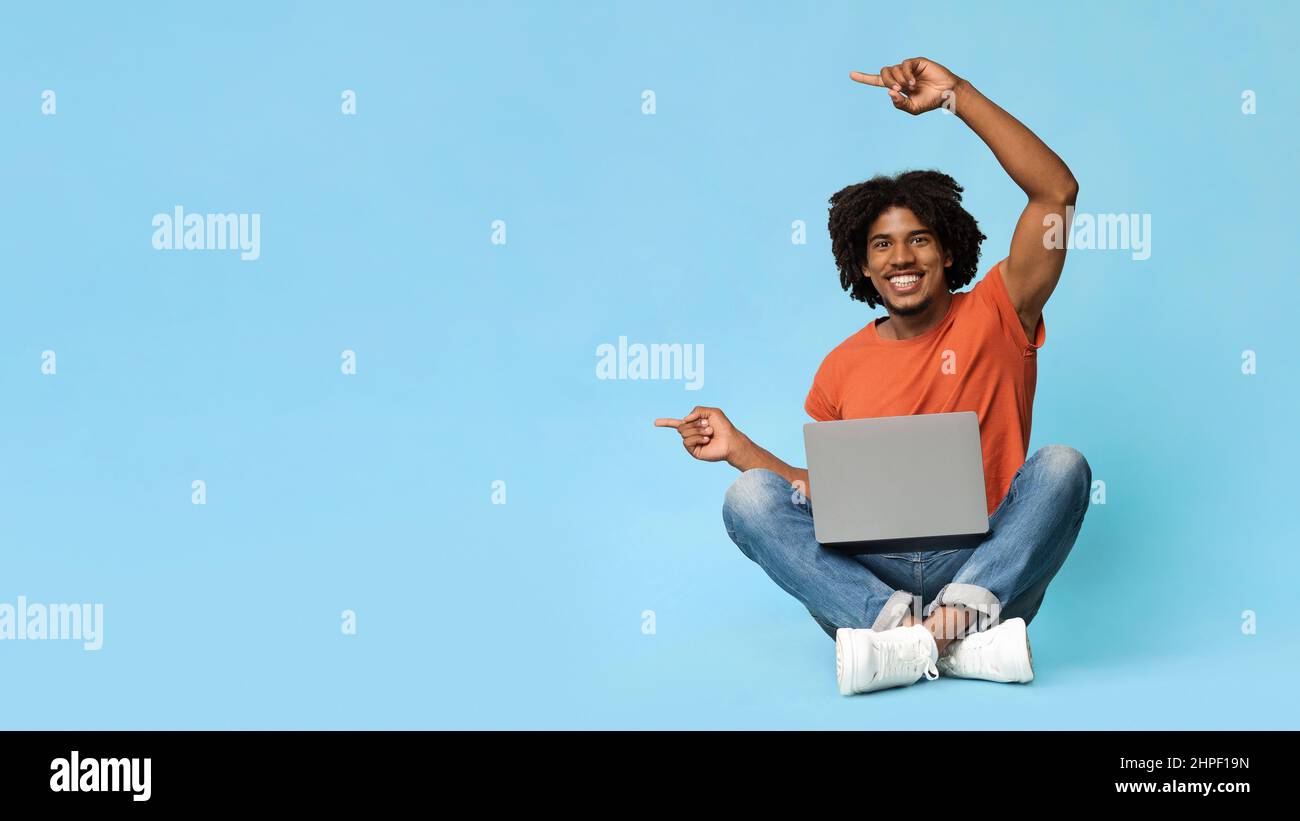 Handsome black man using modern laptop, pointing at copy space Stock ...