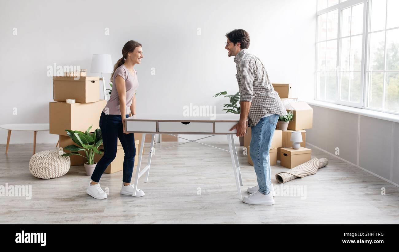 Smiling young caucasian female and husband in casual carry table in ...