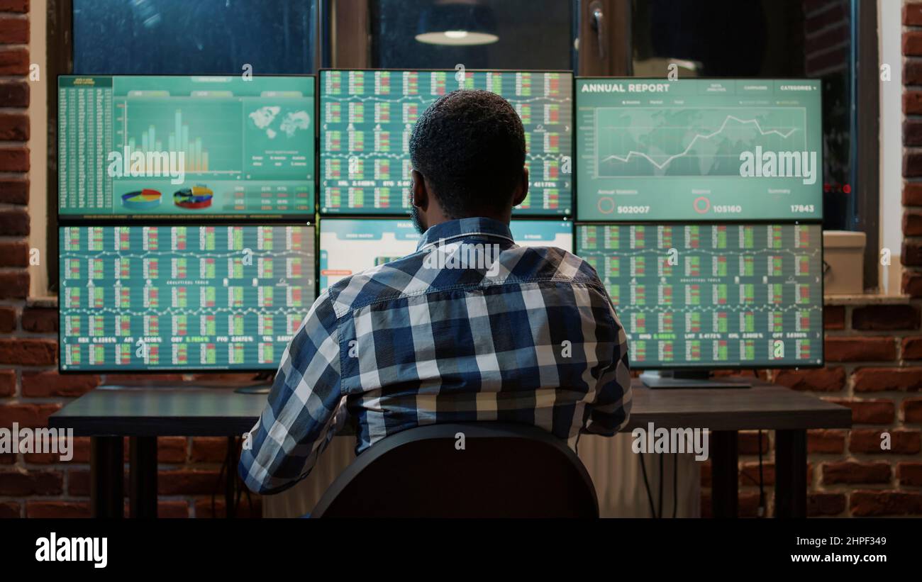 Forex trader analyzing market charts to plan commodities exchange on multi monitor workstation ...