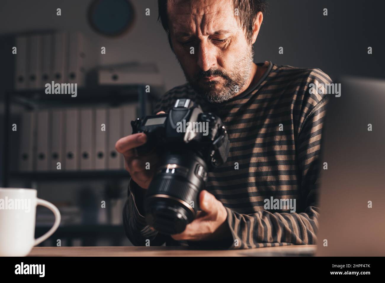 Photographer looking at DSLR camera display at his workplace Stock ...