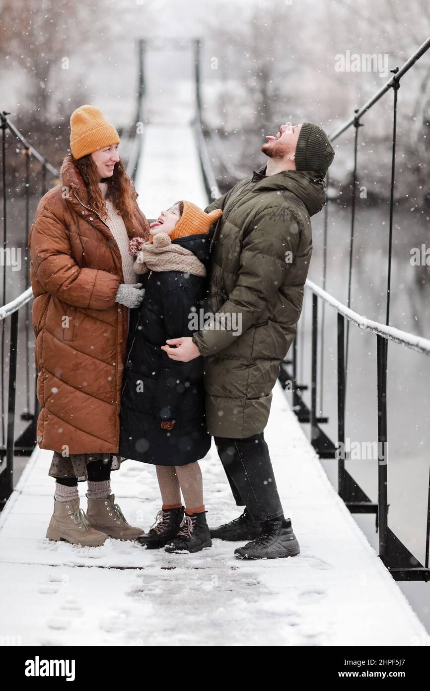 Young mother, father and the little daughter catches snowflakes in a ...
