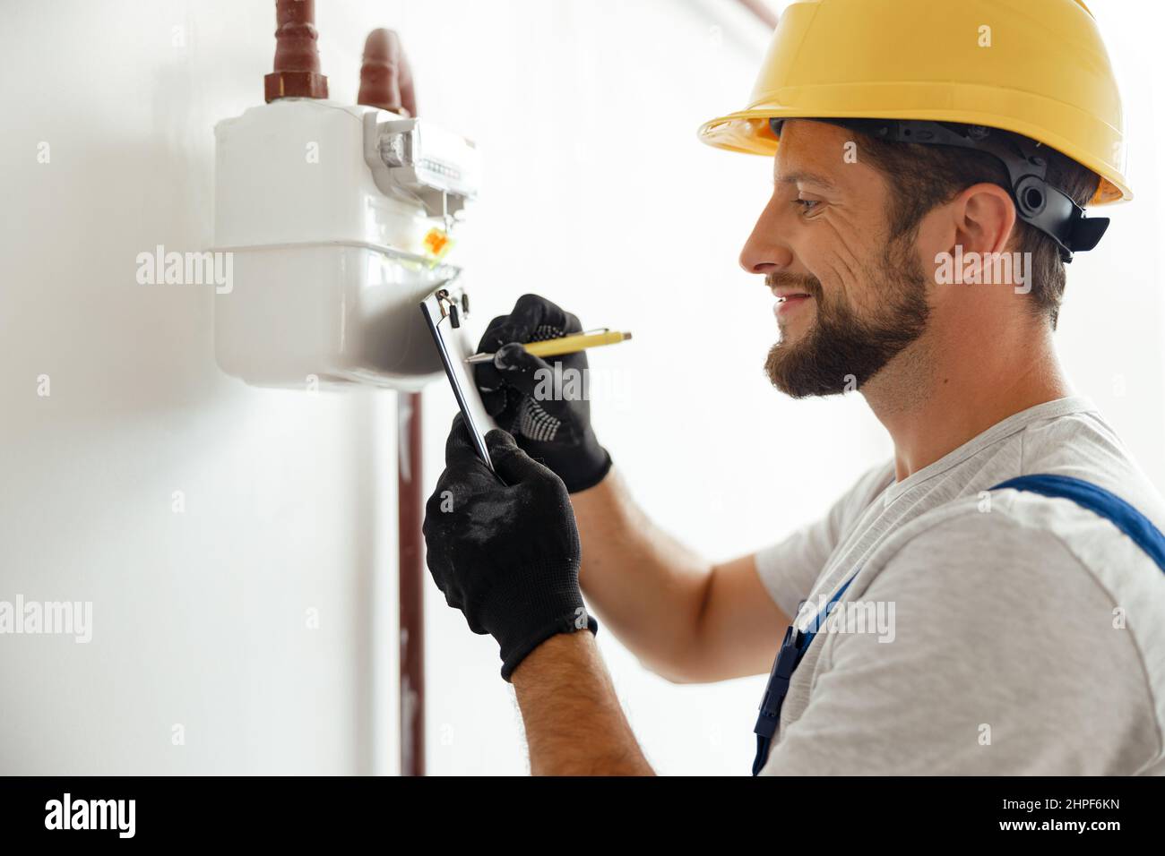 Happy professional heating fitter making notes while checking gas ...