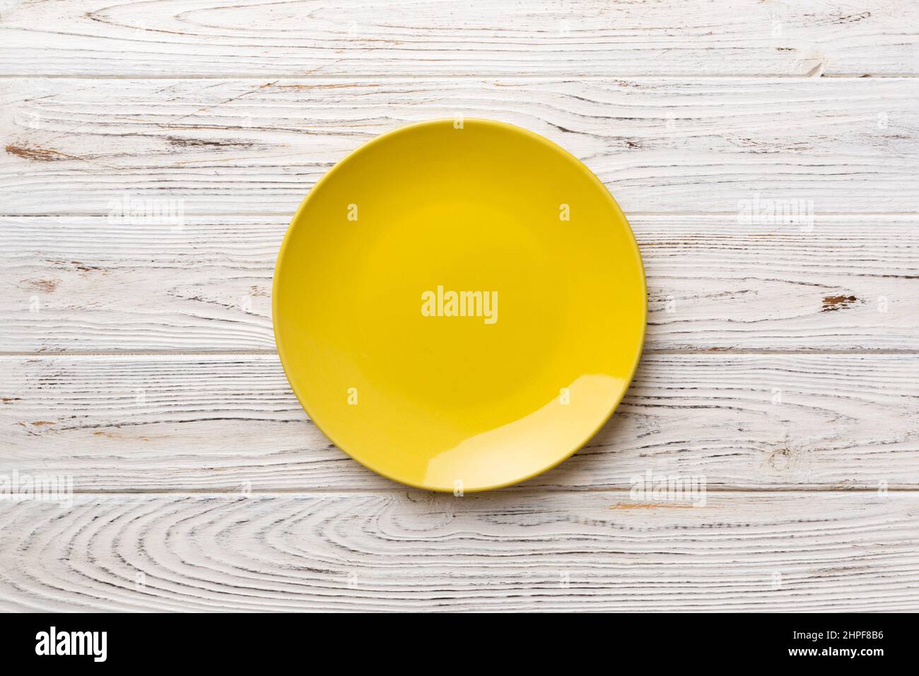 Top view of empty yellow plate on wooden background. Empty space for ...