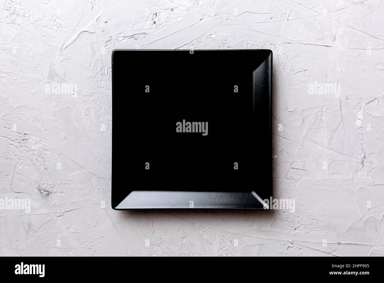 Top view of empty square plate on cement background. Empty space for ...