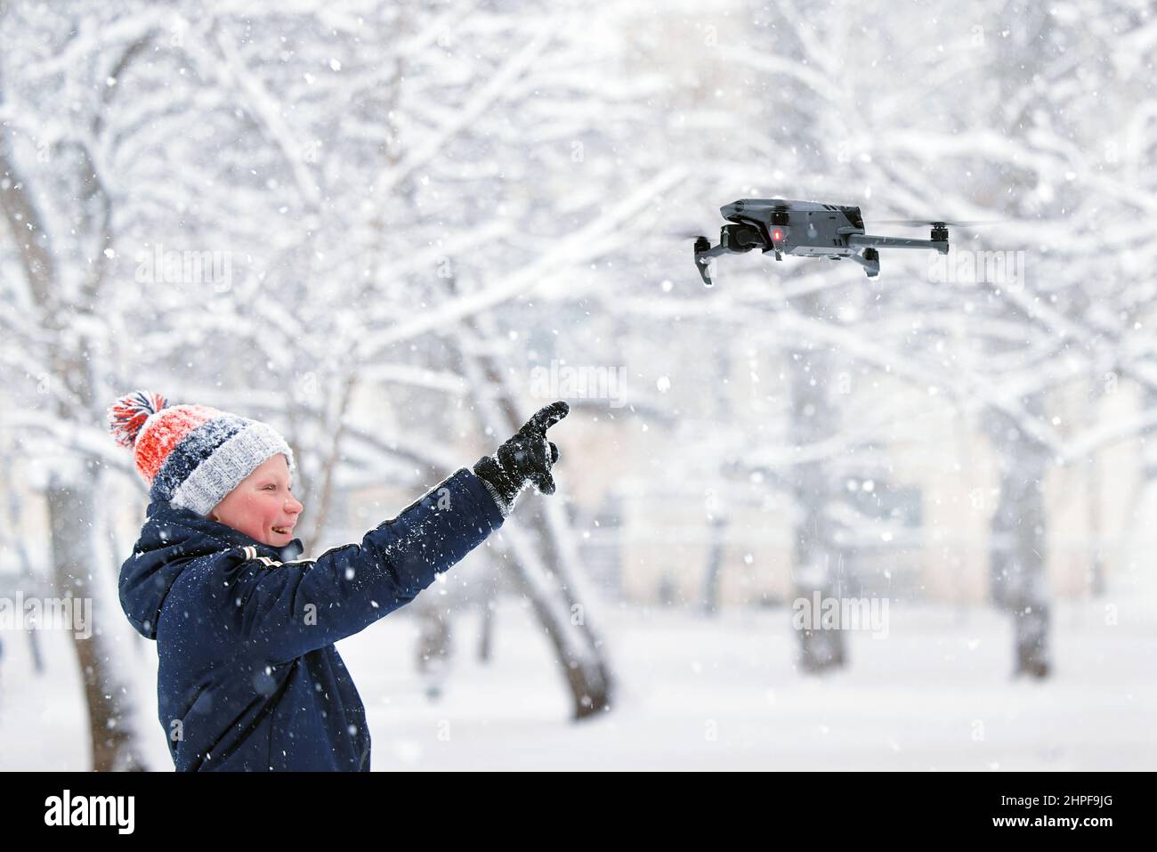 Teenager boy dressed winter jacket and modern digital drone DJI Mavic ...