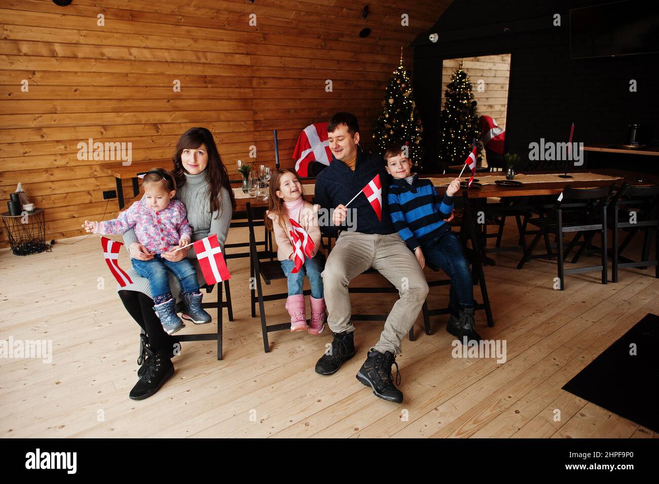 Family with Denmark flags inside wooden house sitting by table. Travel ...