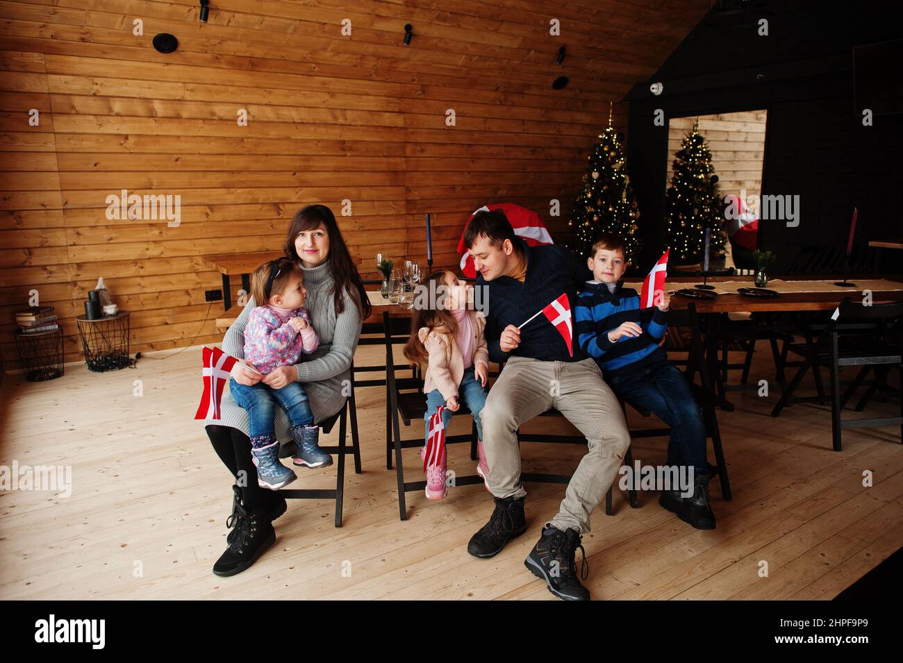 Family with Denmark flags inside wooden house sitting by table. Travel ...