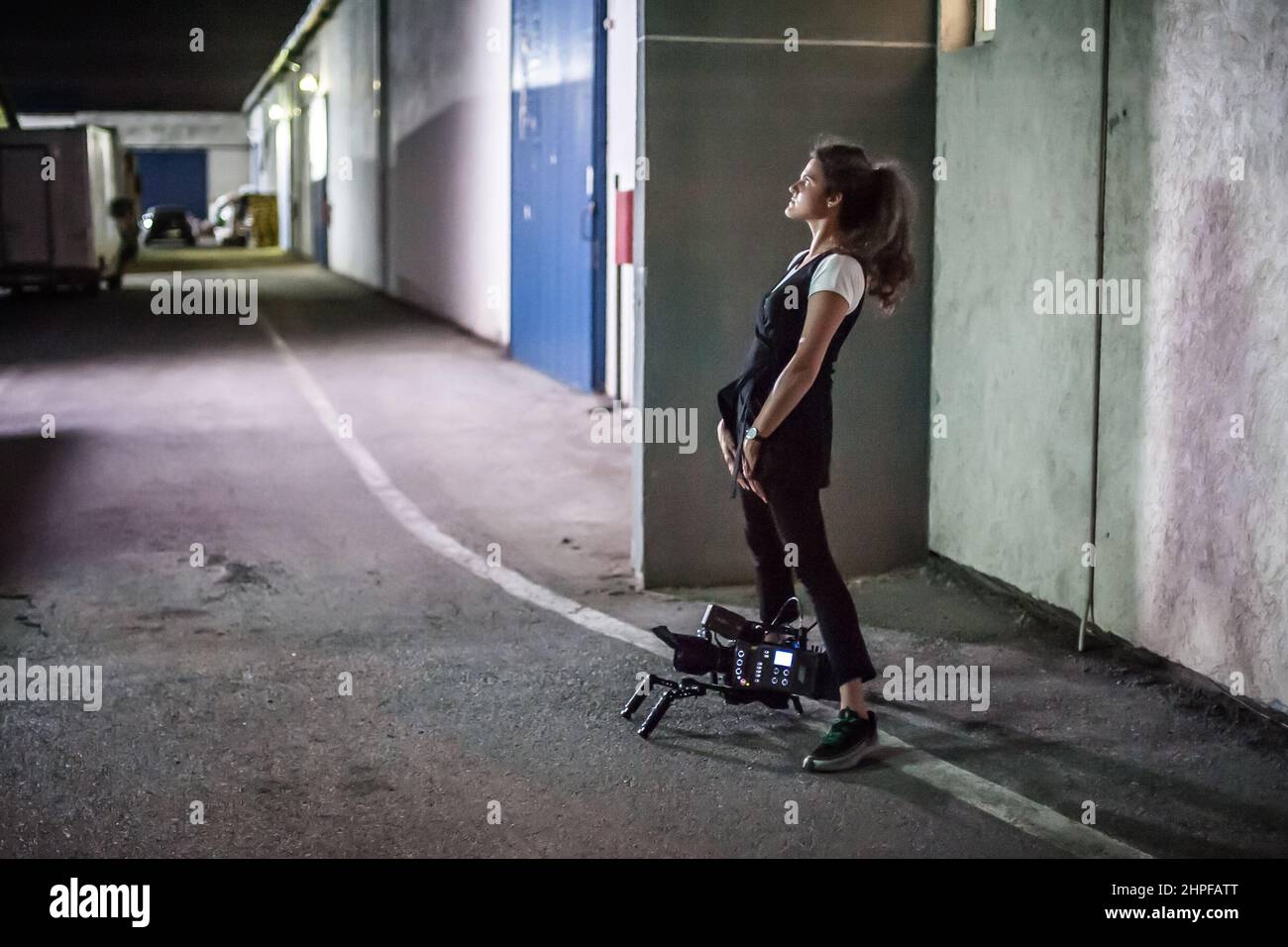 Behind the scenes. Female cameraman with his camera takes a break from ...