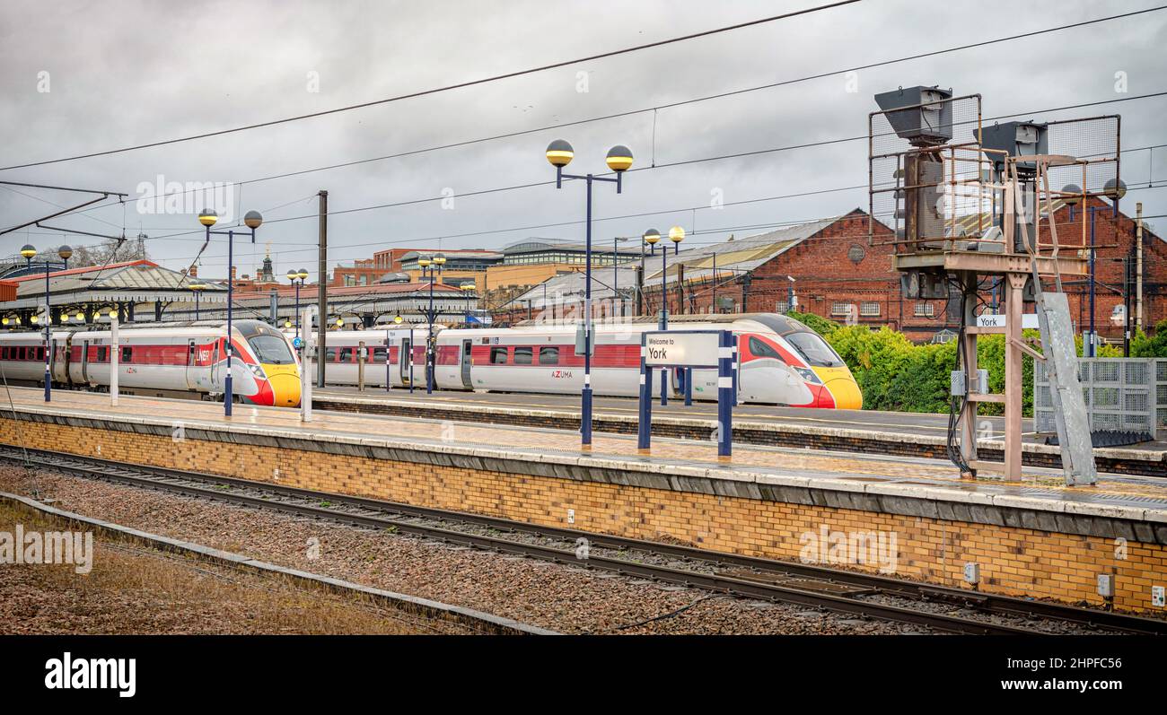 Two trains rest at a railway station platform with historic canopies ...