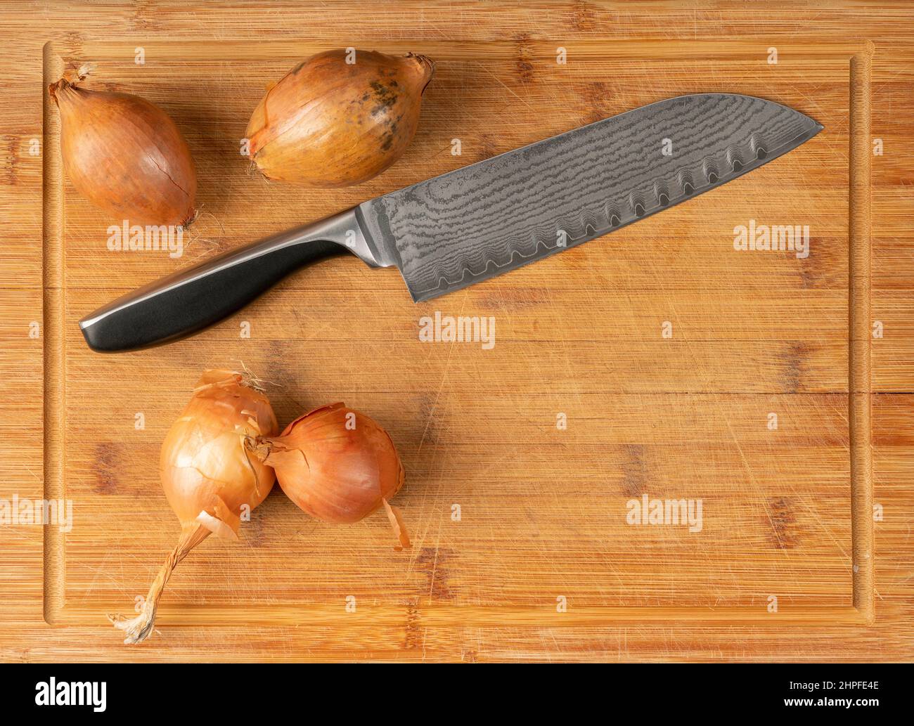 Pattern-welded knife and some onions on wooden bamboo cutting board ...