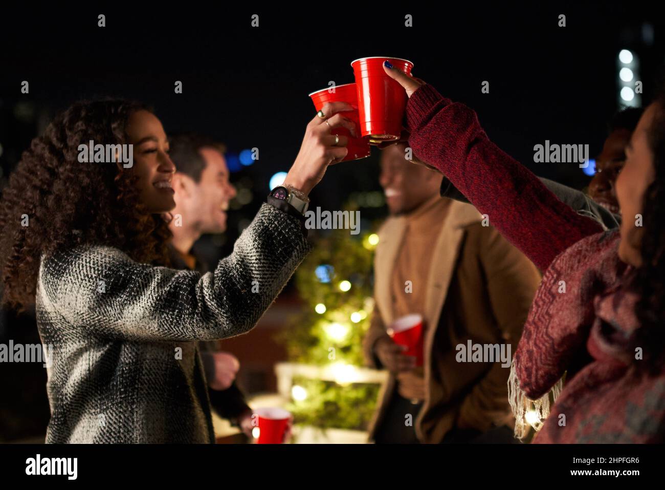 Diverse group of multi-racial friends saying cheers with red cups ...