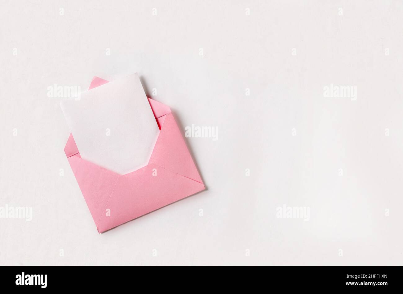 open pink envelope with white paper sheet on white background with ...