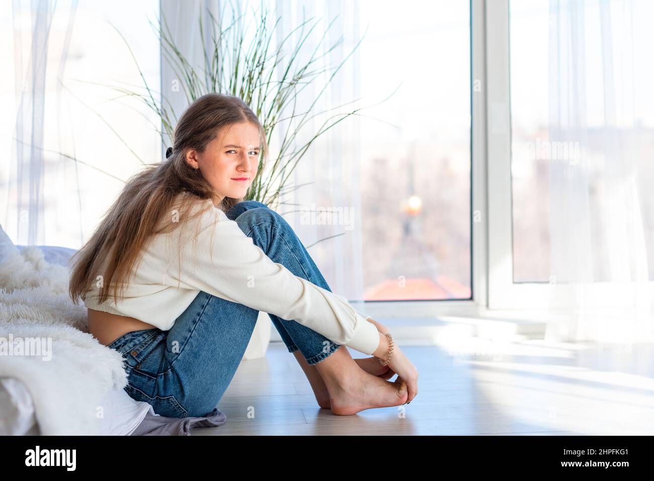 Sad and angry teenage girl sitting on the floor in the room. Teenager ...