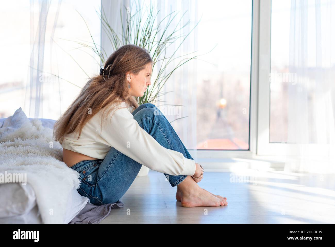 Sad and angry teenage girl sitting on the floor in the room. Teenager ...
