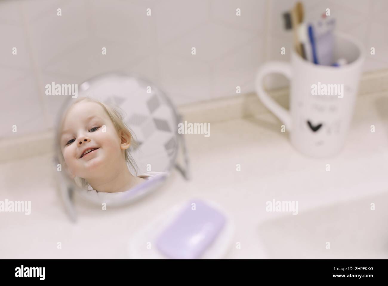 little funny girl brushing teeth and washing hands in the bathroom ...
