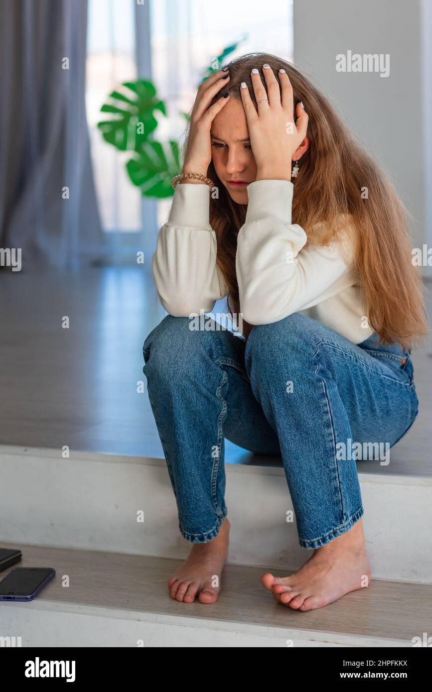 Sad and angry teenage girl sitting on the floor in the room. Teenager ...