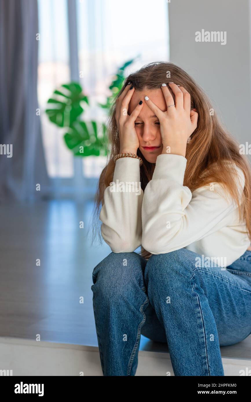 Sad and angry teenage girl sitting on the floor in the room. Teenager ...
