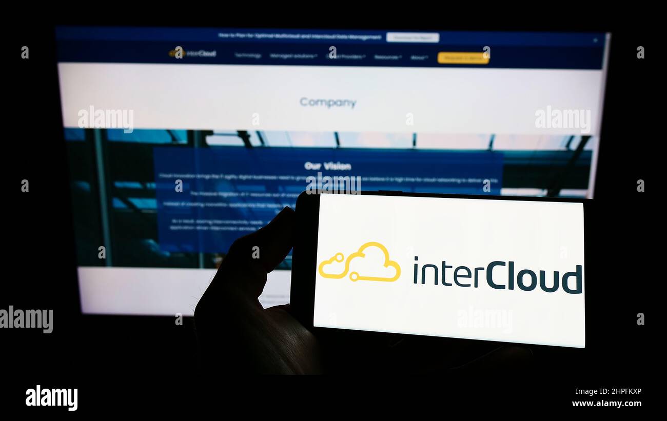 Person holding cellphone with logo of French network solutions company InterCloud S.A.S. on ...