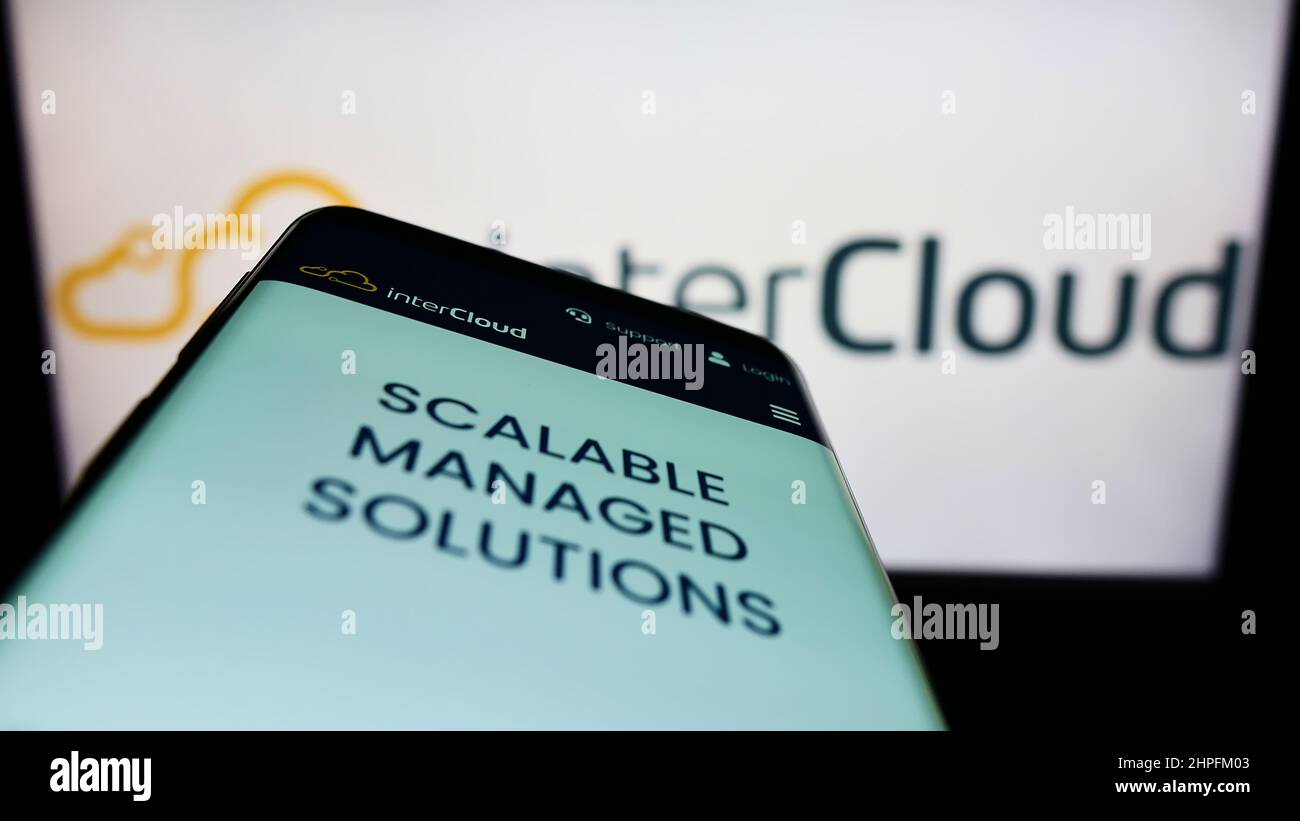 Smartphone with webpage of French network solutions company InterCloud SAS on screen in front of ...