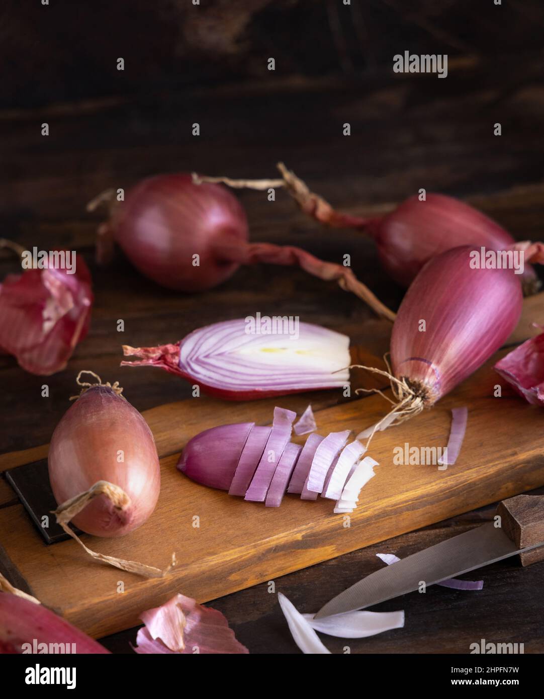 Sliced Red tropea onions with a knife on a wooden board close up ...
