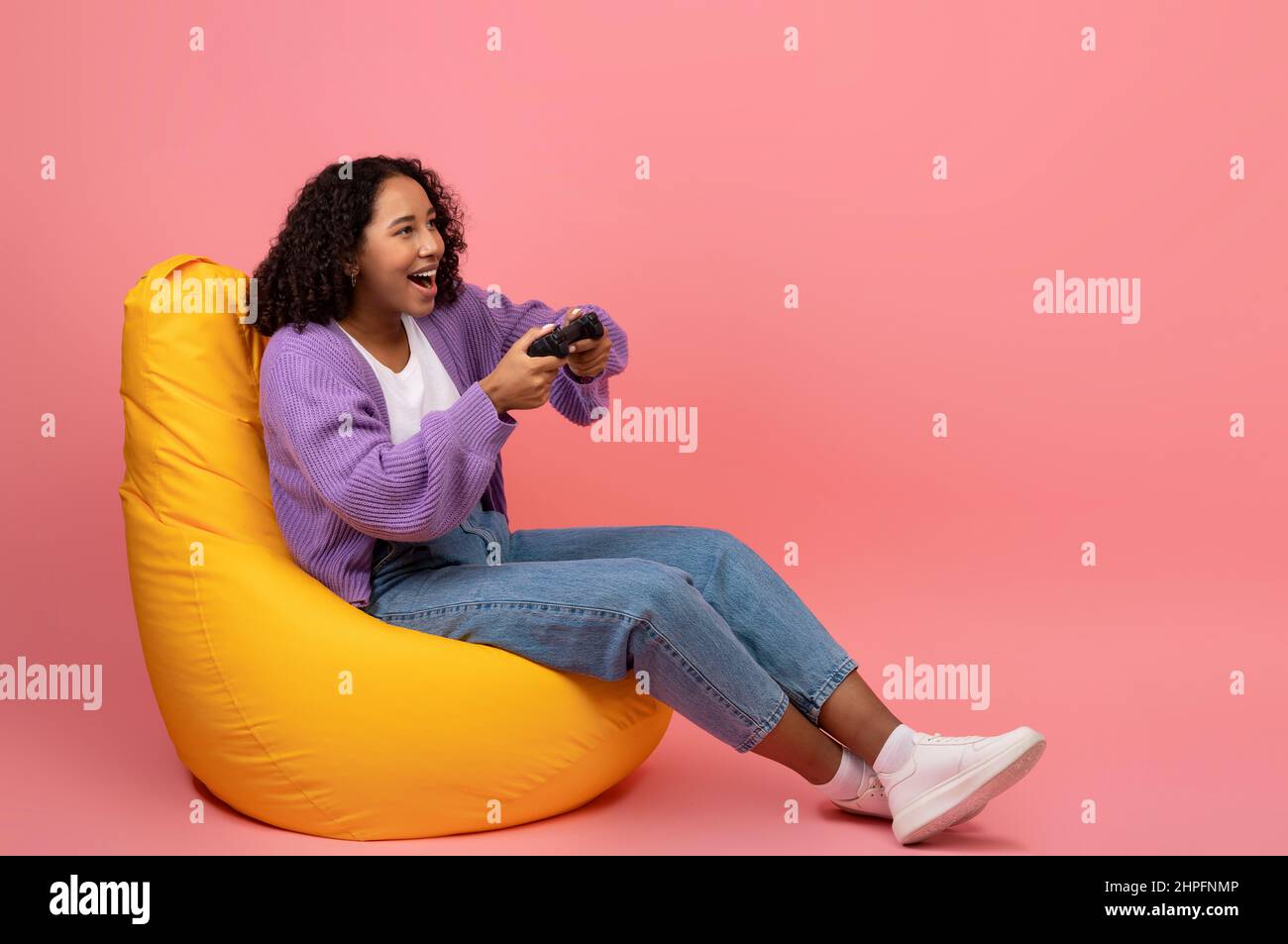Excited black female gamer with joystick playing online computer game ...
