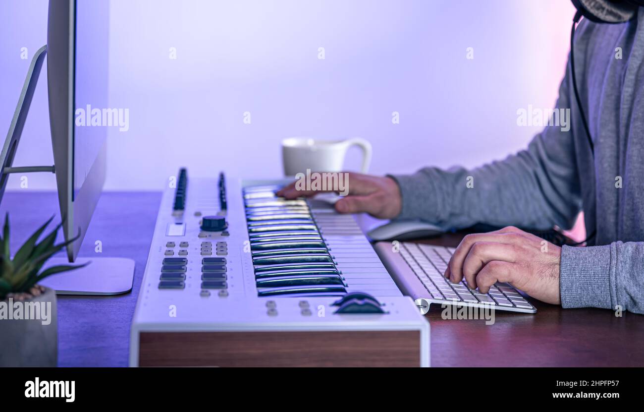 Male musician creates music using computer and keyboard, musician ...
