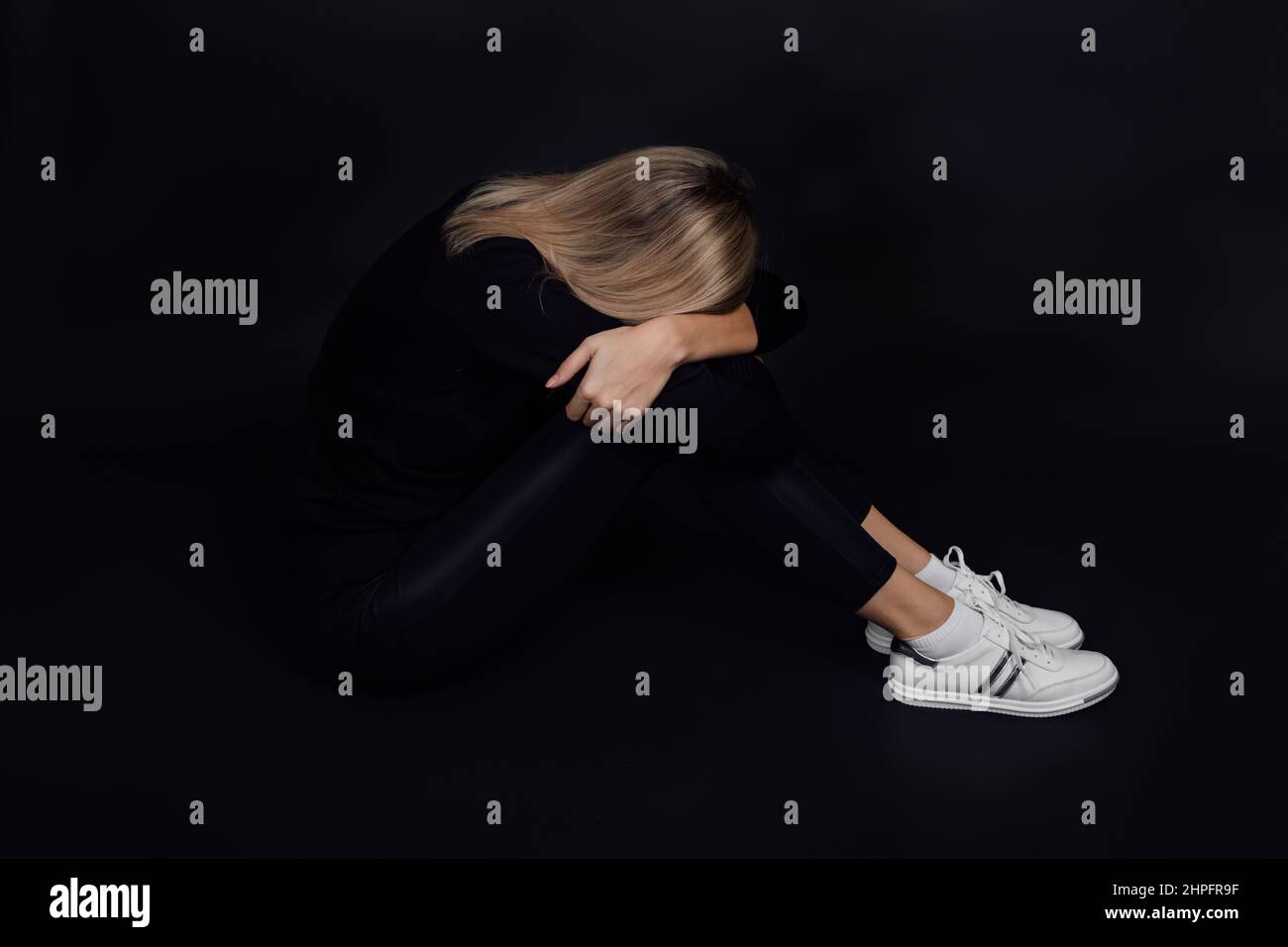 Reserved Caucasian blonde woman closed from world sitting on floor with ...