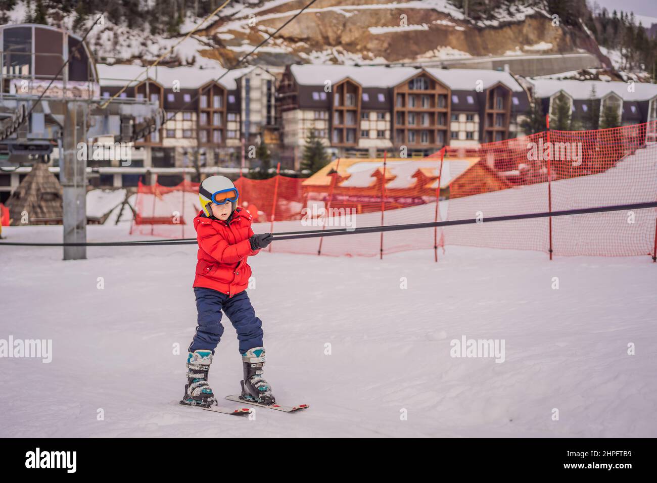 Boy uses a training lift. Child skiing in mountains. Active toddler kid ...