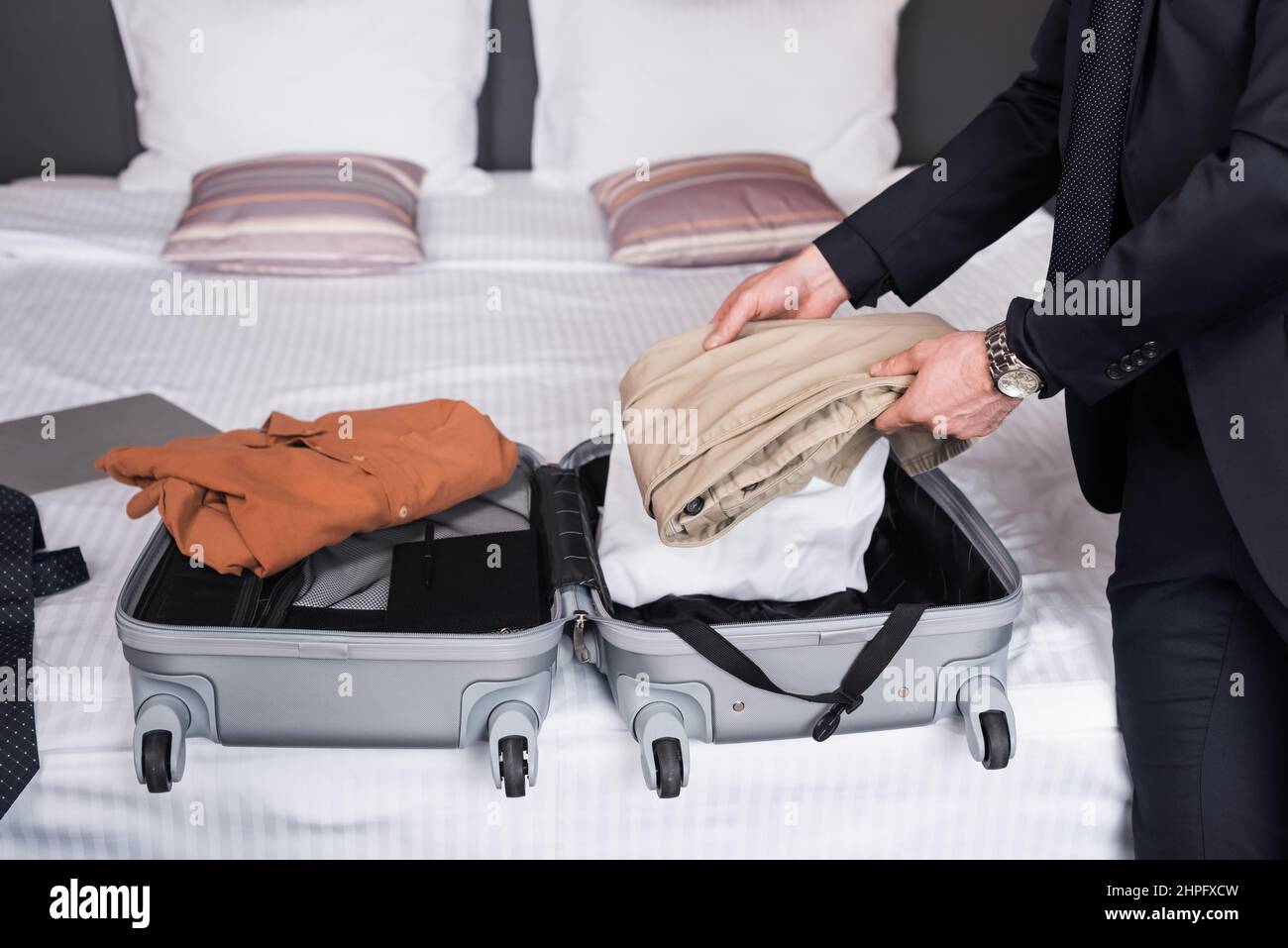 cropped view of man in suit unpacking baggage in hotel room Stock Photo ...