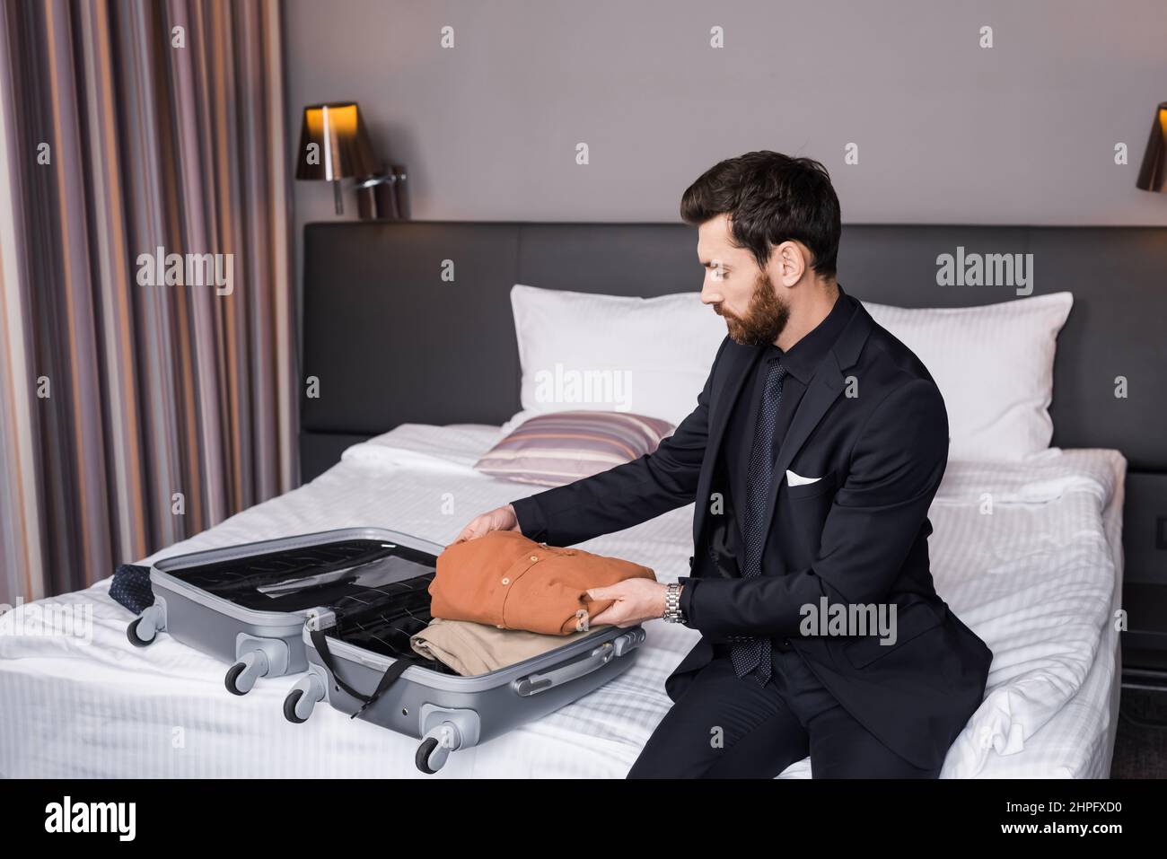 bearded man in suit unpacking baggage in hotel room Stock Photo - Alamy
