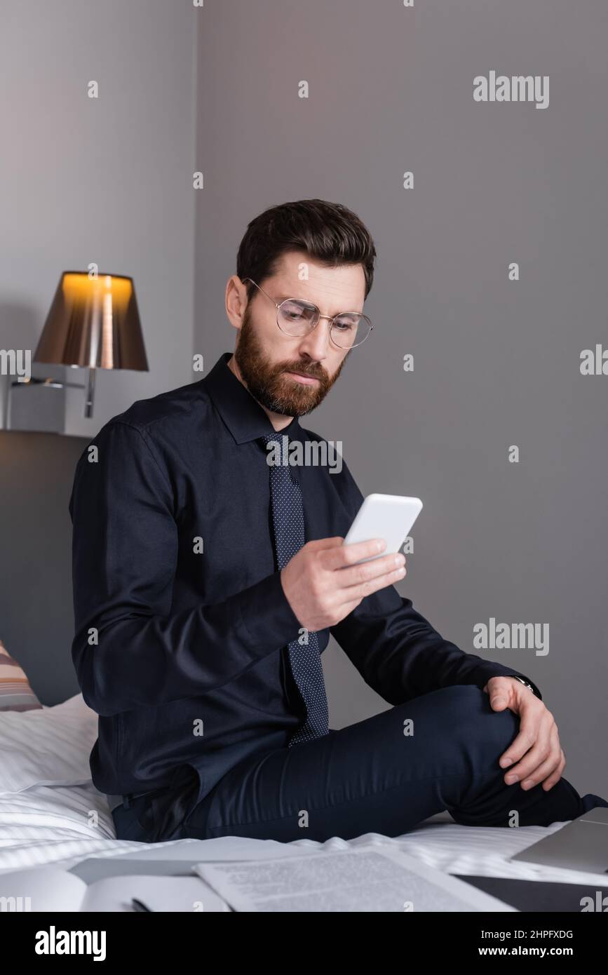 bearded man in suit and eyeglasses using smartphone in hotel Stock ...