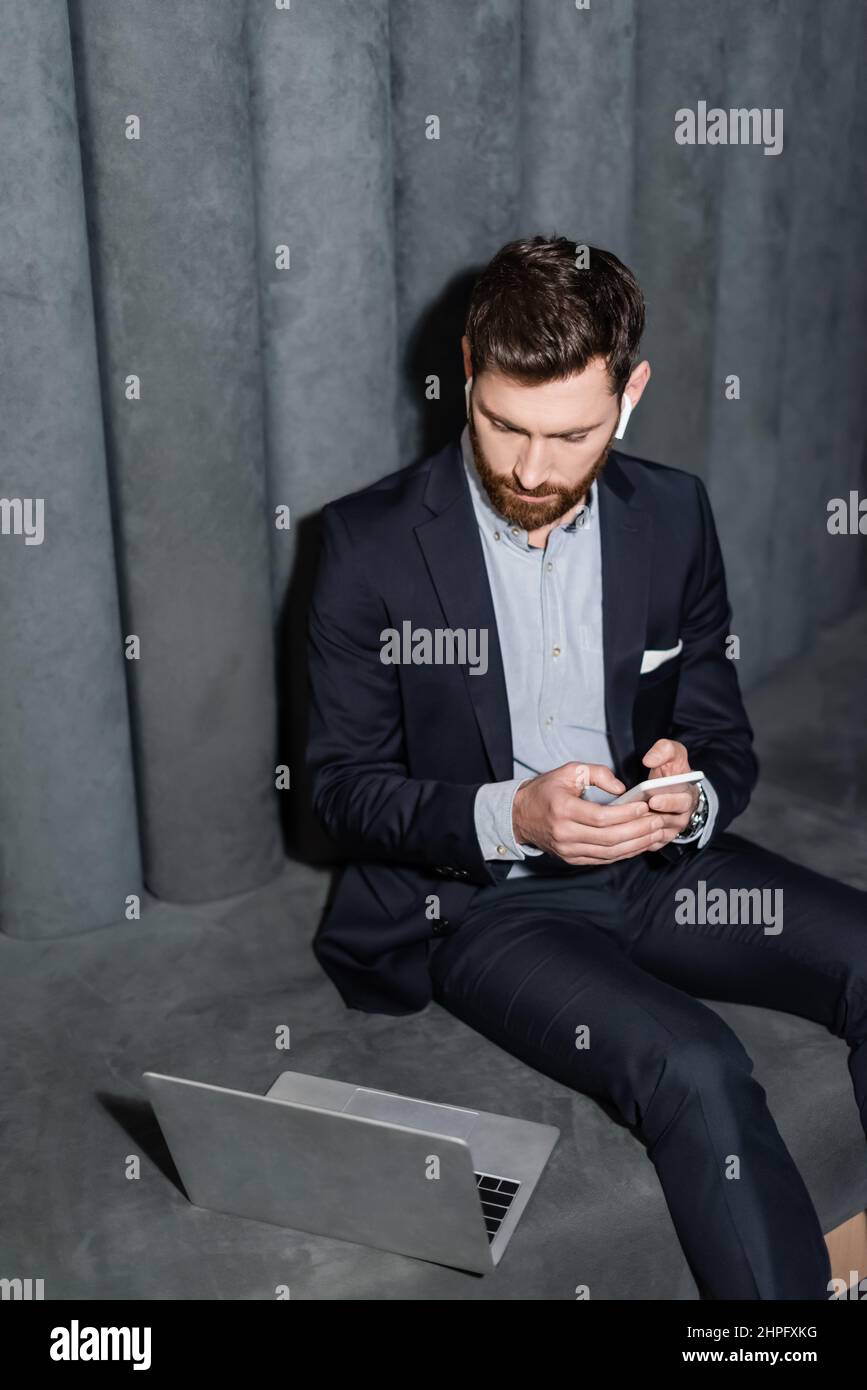 bearded man in earphones holding smartphone in hotel lobby Stock Photo ...