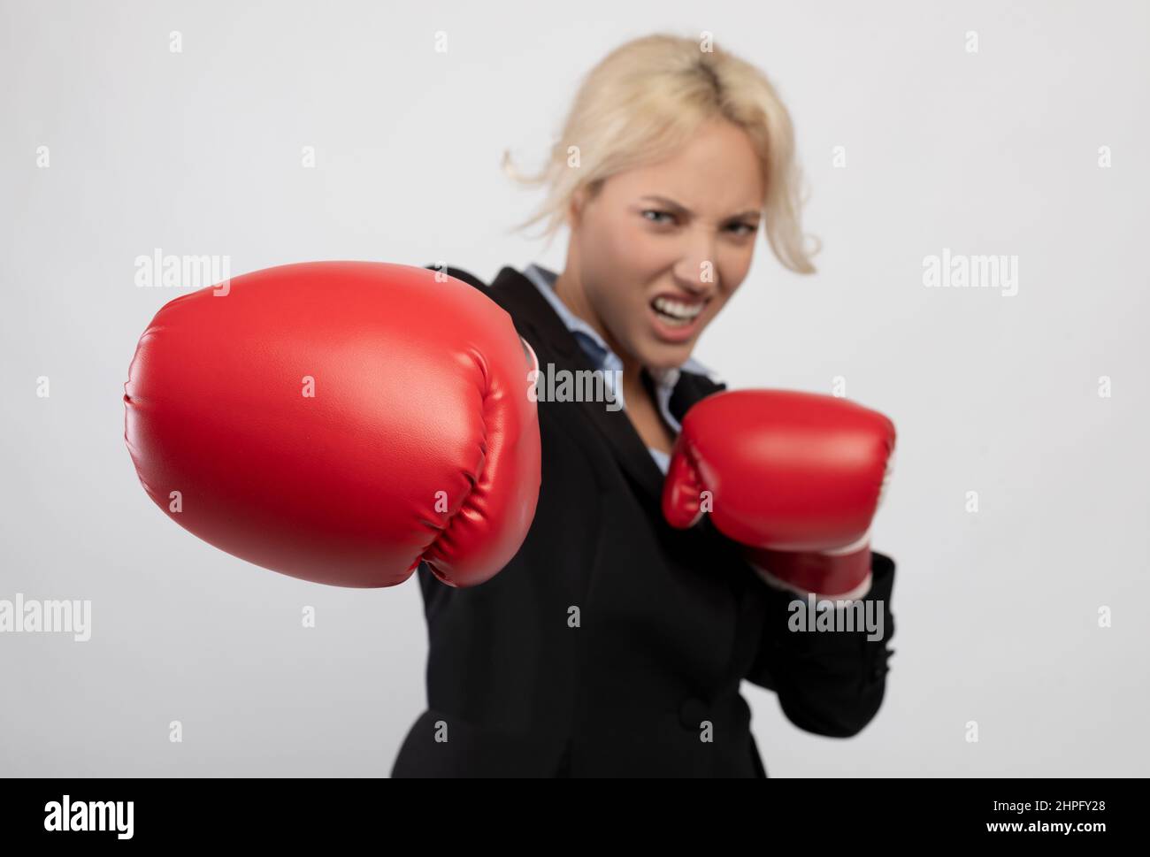 Young boxing businesswoman punching towards camera wearing red boxing ...