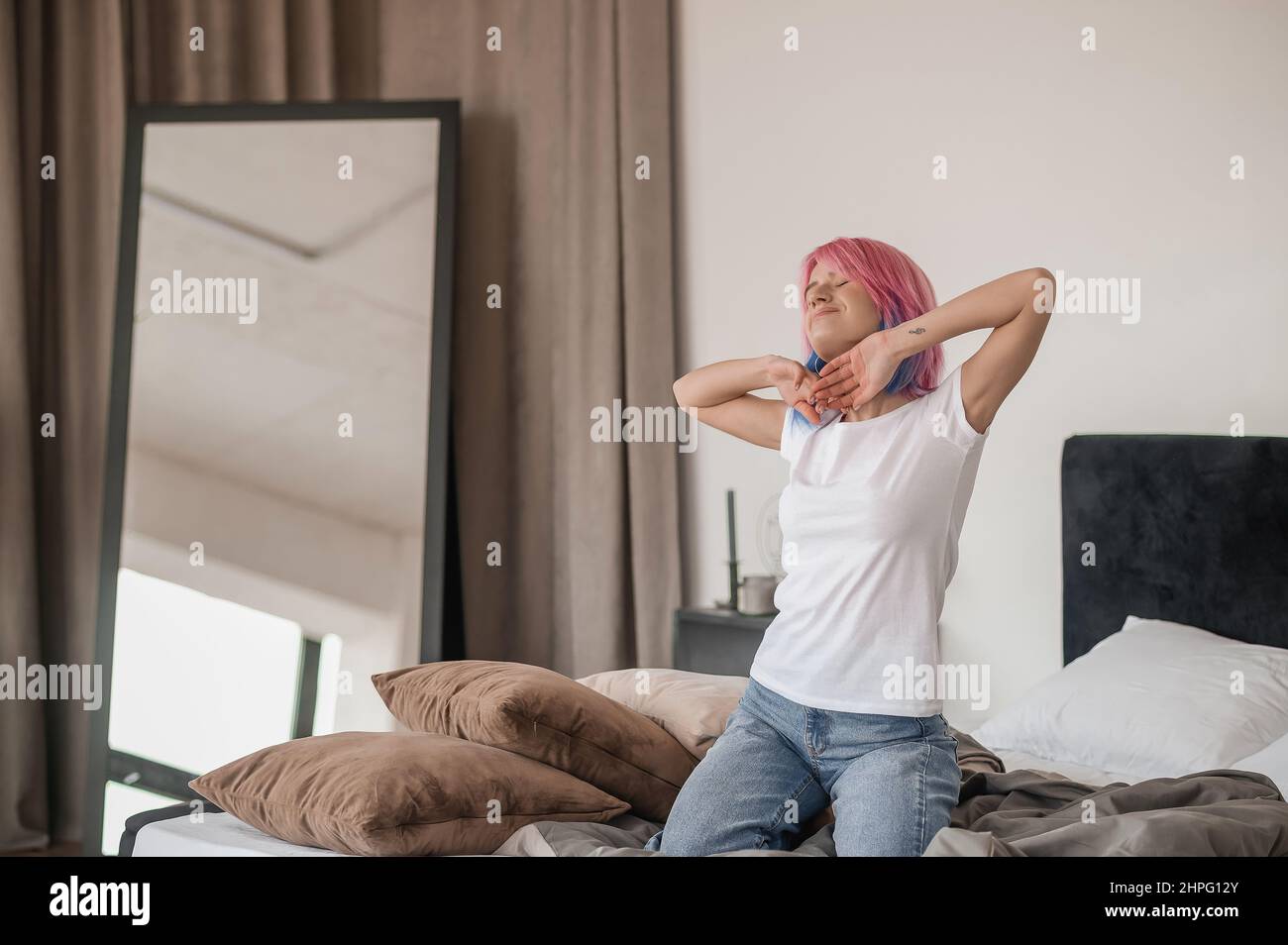 Pink-haired young girl lying in bed and looking sleepy Stock Photo - Alamy