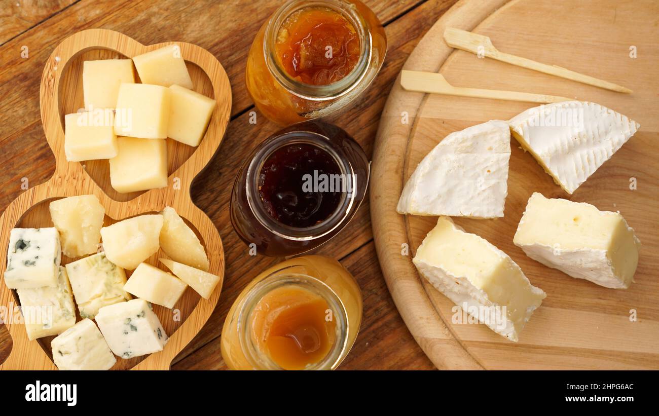 Jars of homemade jams and honey and a variety of cheeses on a wooden ...