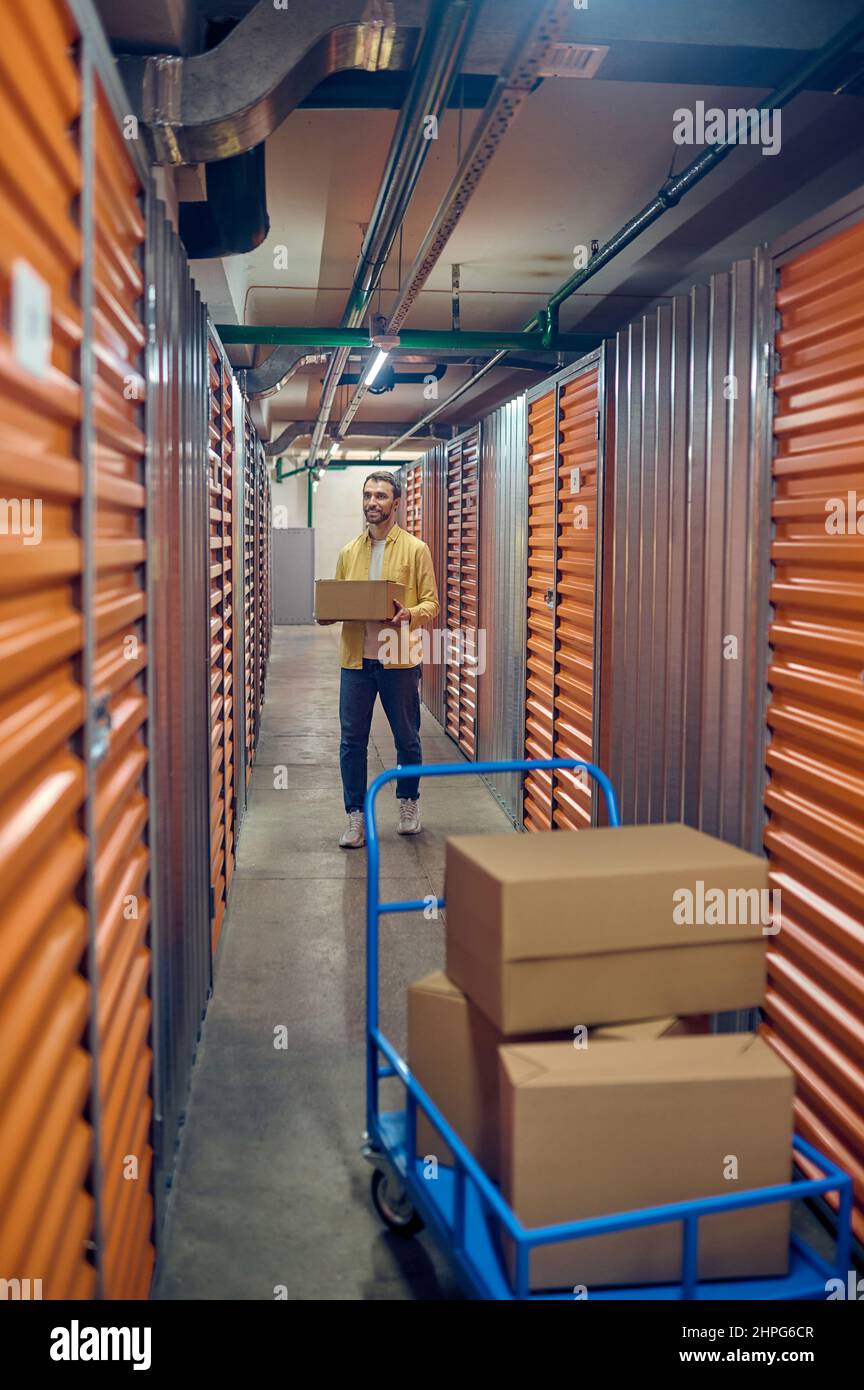 Warehouse order picker standing in the aisle among cargo containers ...