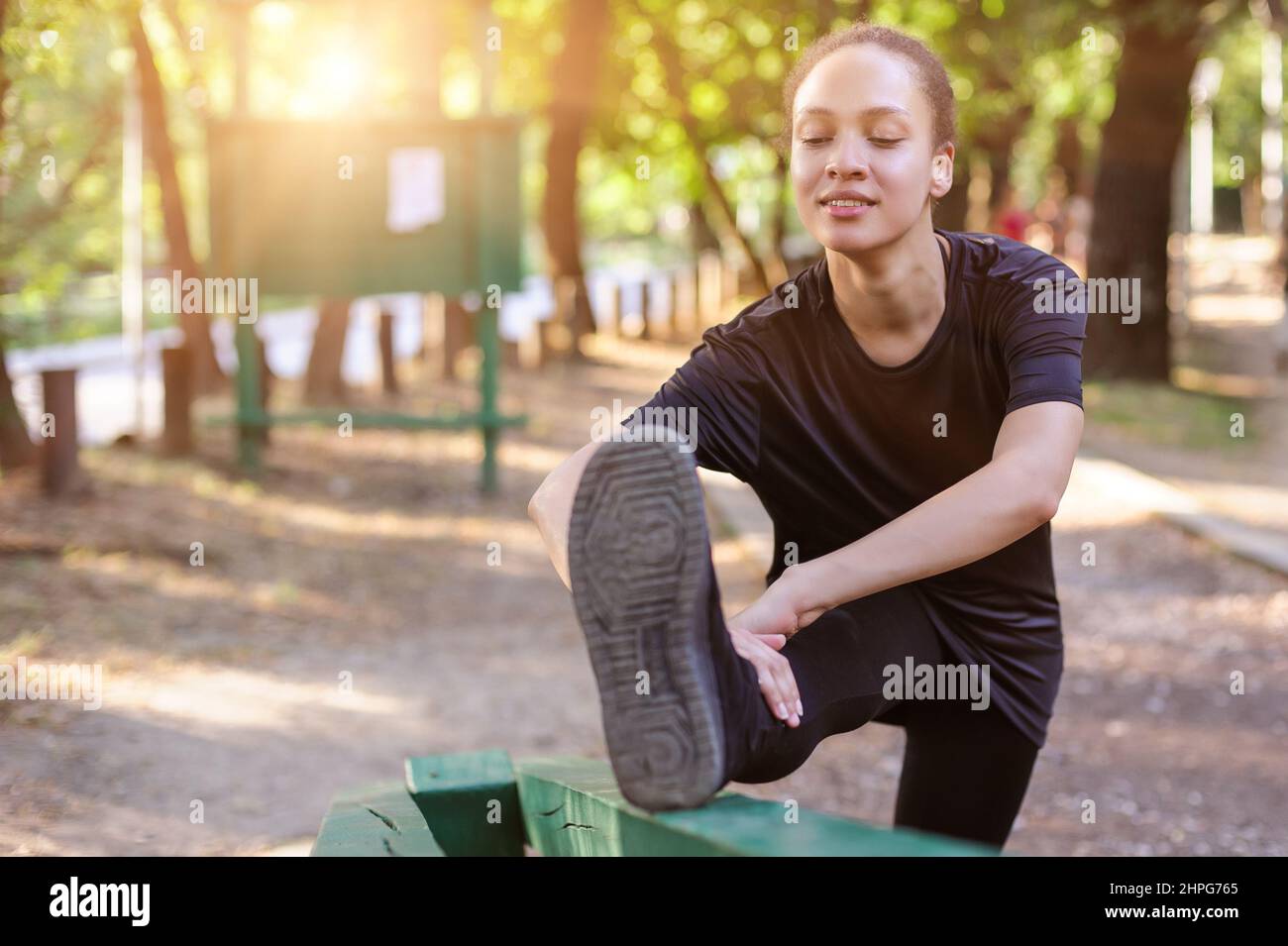 Training outdoors. Fit young woman stretching her legs to warm up ...